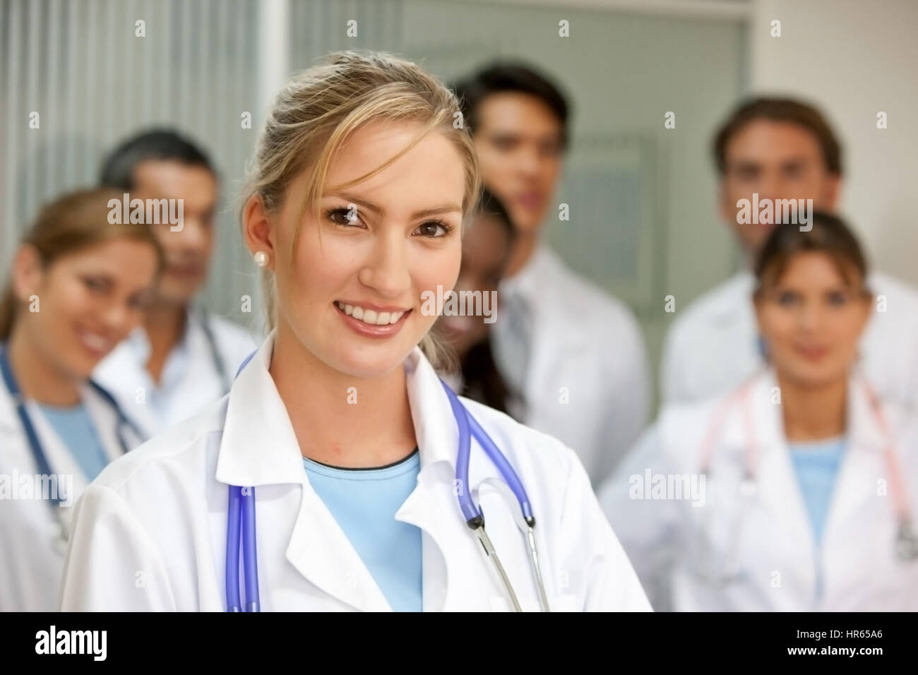 female doctor smiling in a hospital with her team behind Stock Photo ...
