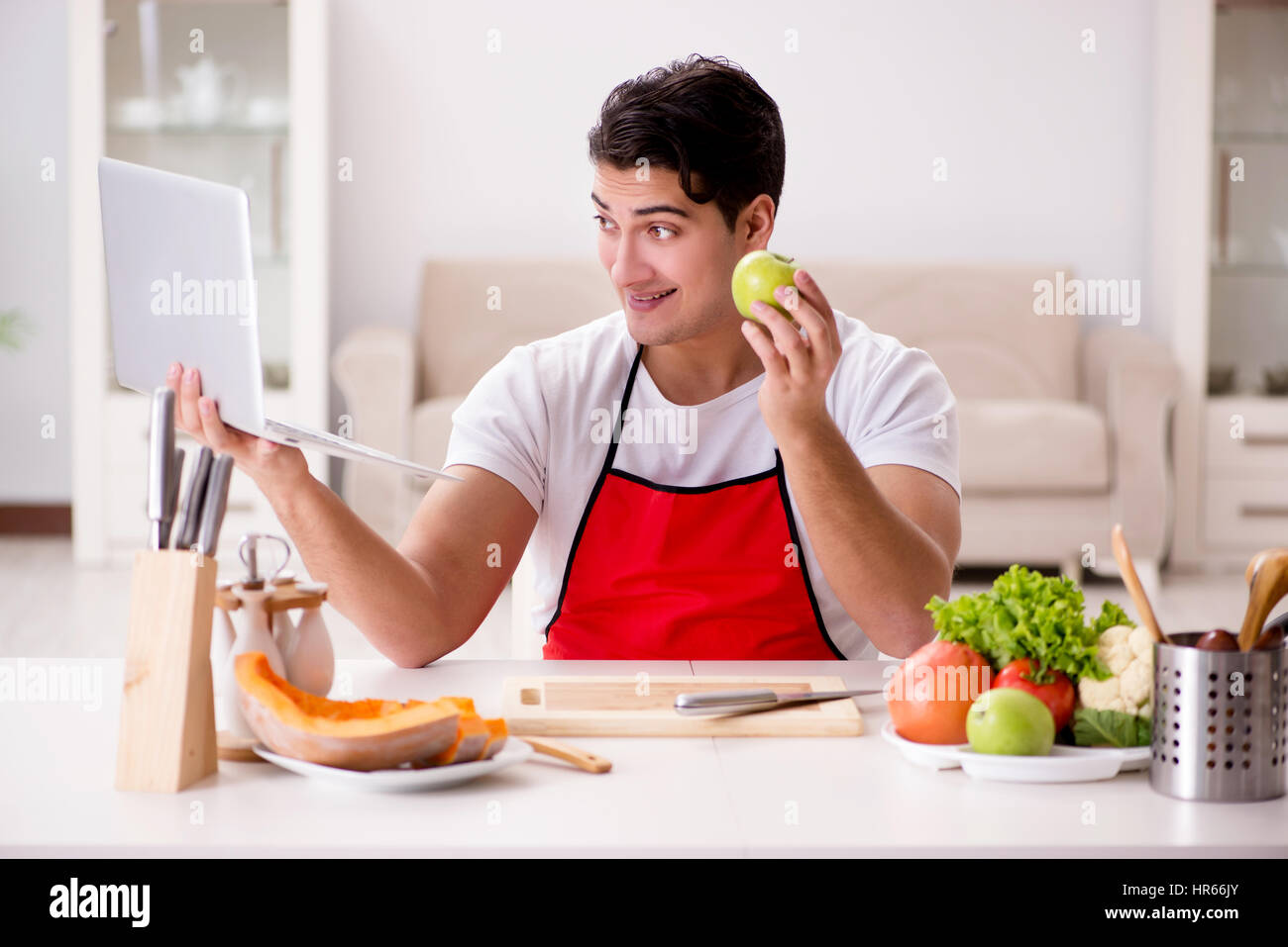 Man with laptop preparing food at the kitchen Stock Photo - Alamy