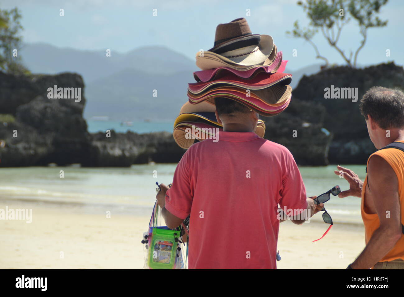 Man is selling hats on a beach on Boracay island. Lots of hats on his ...