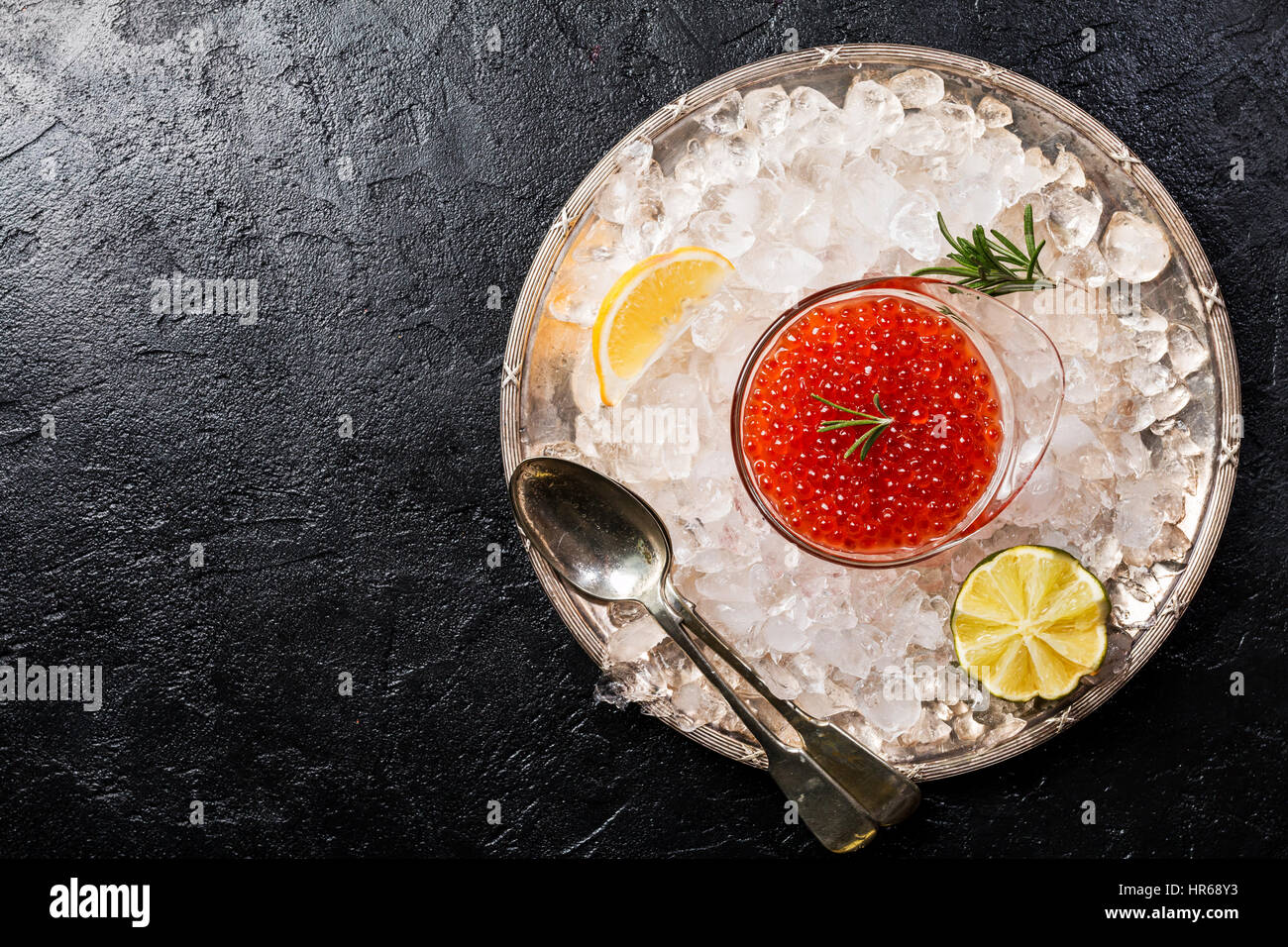 Glass bowl with red caviar on ice over black background. Healthy food ...