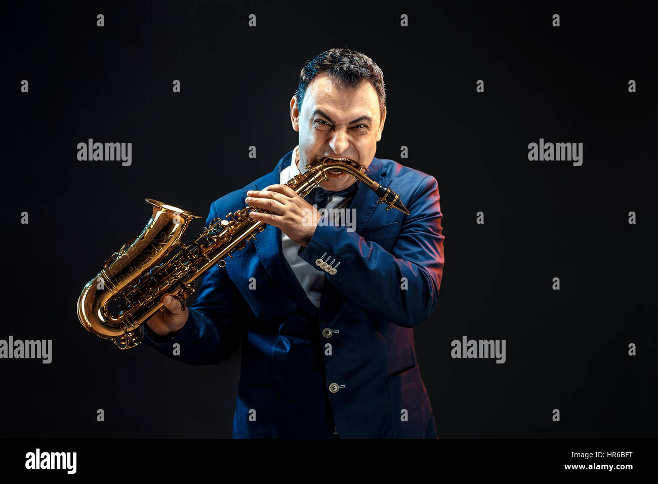 Portrait of angry adult man biting sax.Studio shot.Isolated Stock Photo ...