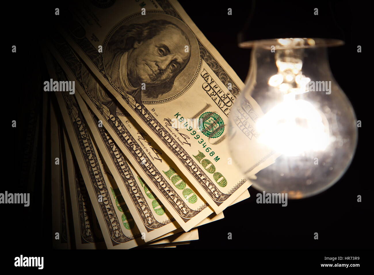 Hanging light bulb dangle on a wire illuminating bank notes Stock Photo ...