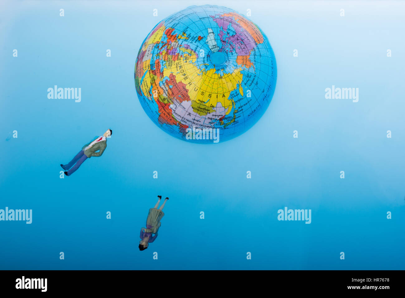 Little globe with floating figurines around in water Stock Photo - Alamy
