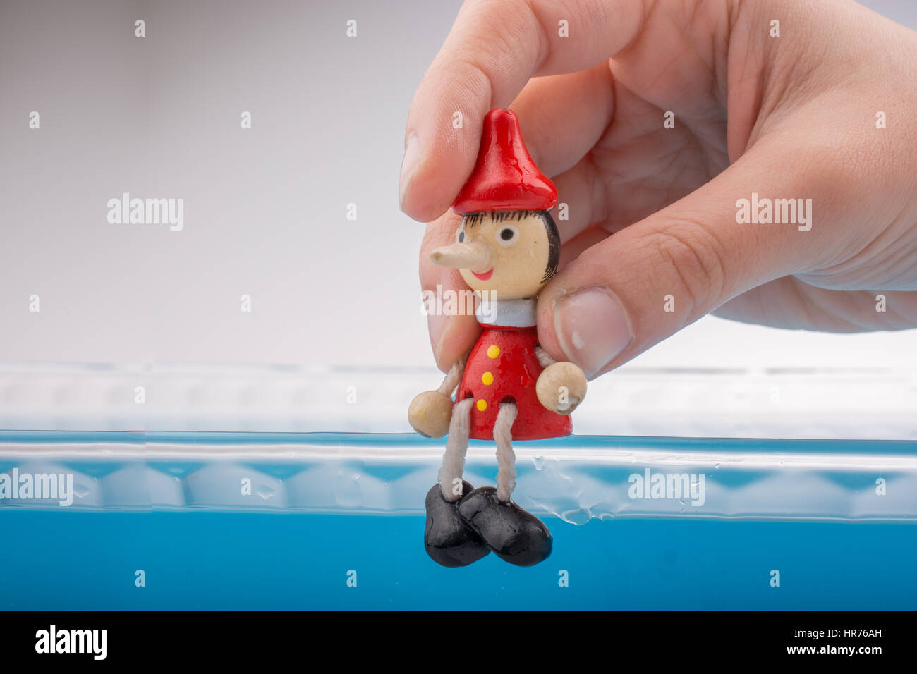 Hand holding wodden puppet Pinocchio on in blue water Stock Photo - Alamy