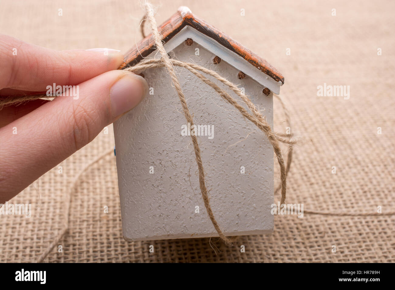 Hand holding a thread around a model house on a brown background Stock ...