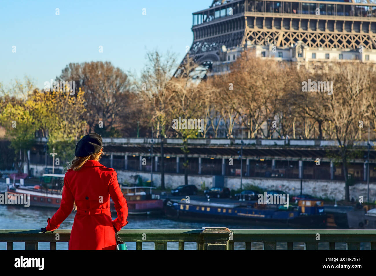 Bright in Paris. Seen from behind trendy woman in red trench coat ...