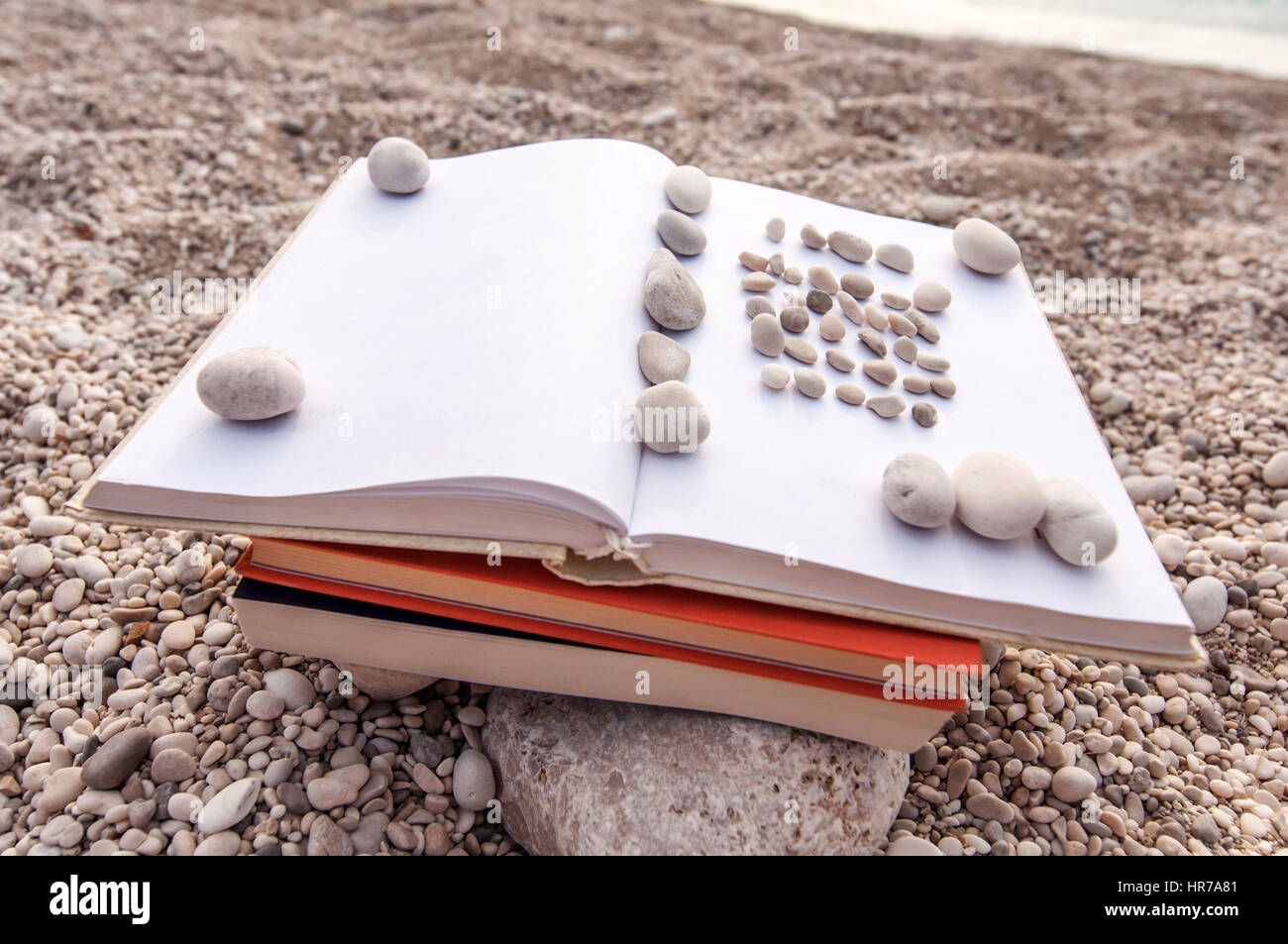Open book at beach on a pile of books near the sea during summer sunset ...