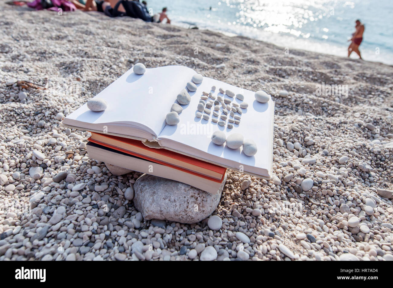 Open book at beach on a pile of books near the sea during summer sunset ...