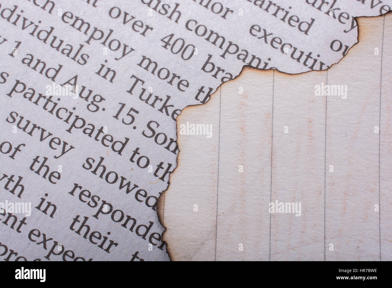 Piece of burnt paper placed on texted paper Stock Photo - Alamy