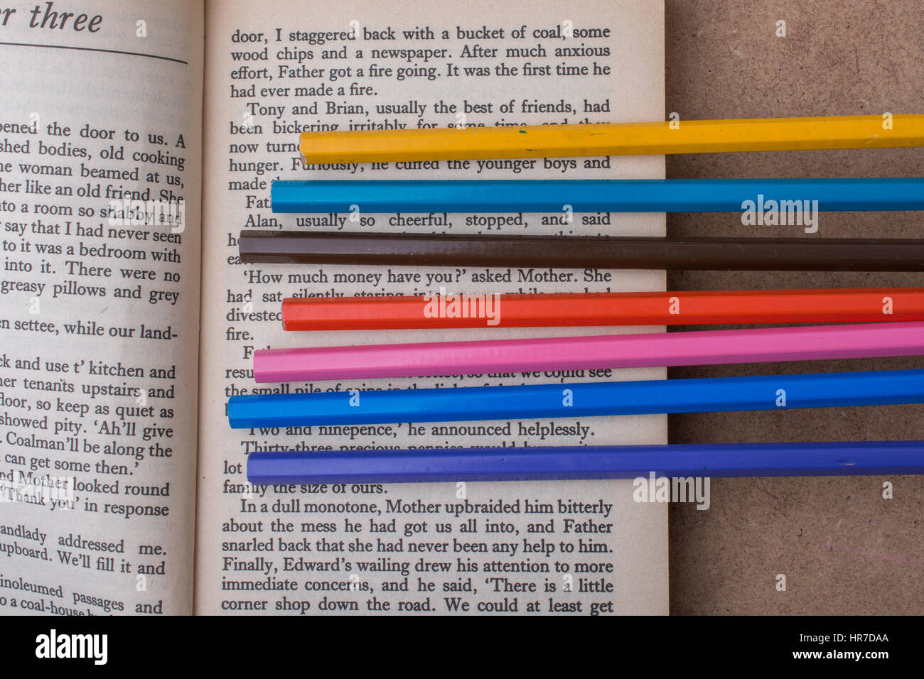 Color pencils placed on the page of a book with text Stock Photo - Alamy