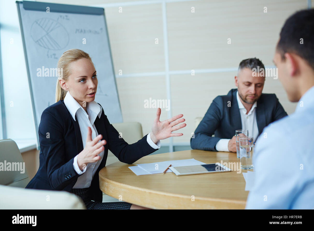 Elegant blond businesswoman gesturing actively while briefing her ...