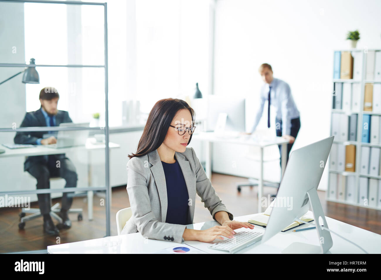 Several business people busy working in modern office at desks with ...