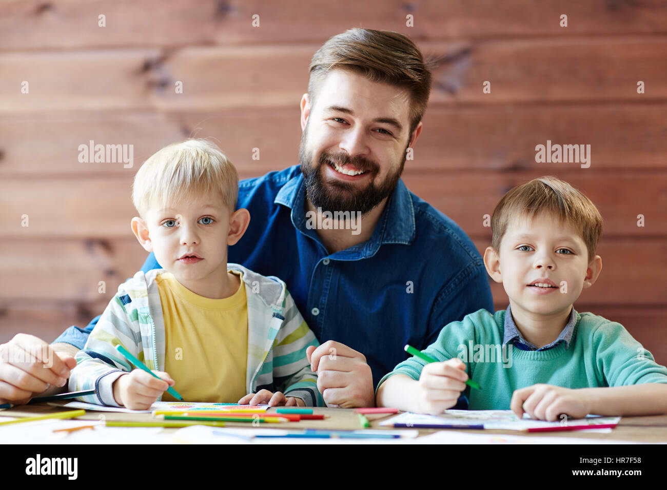 Portrait of happy loving family: two brothers drawing with pencils and ...