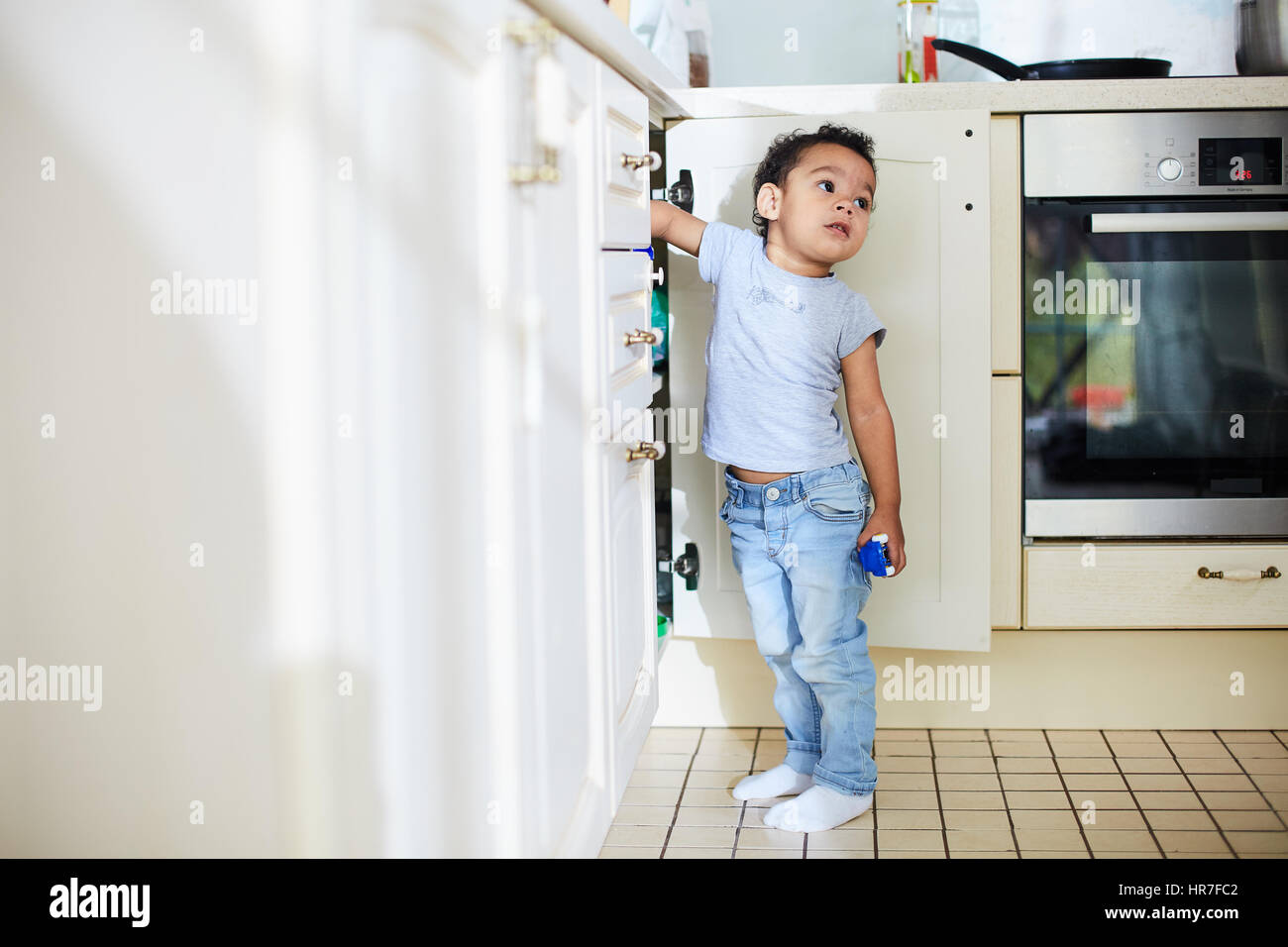 Full-length portrait of playful toddler boy with toy car in hand trying ...