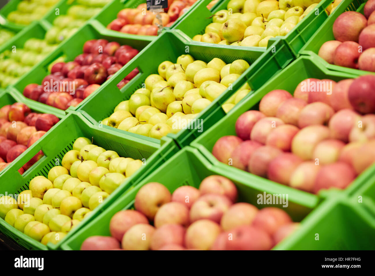 Fresh tasty green, yellow and red apples lying in green plastic boxes ...