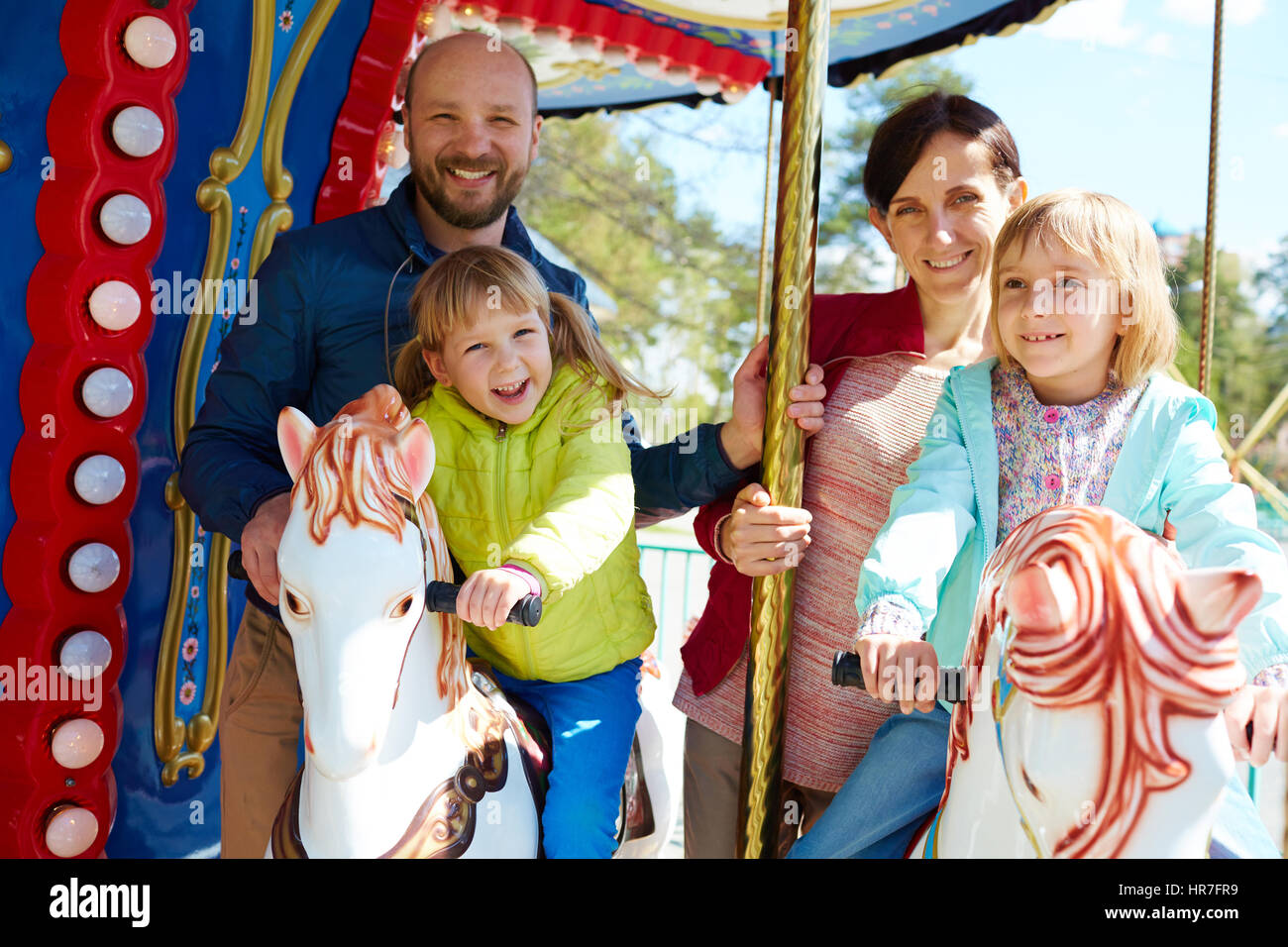 Pretty little girl in green windbreaker and her elder sister riding on ...