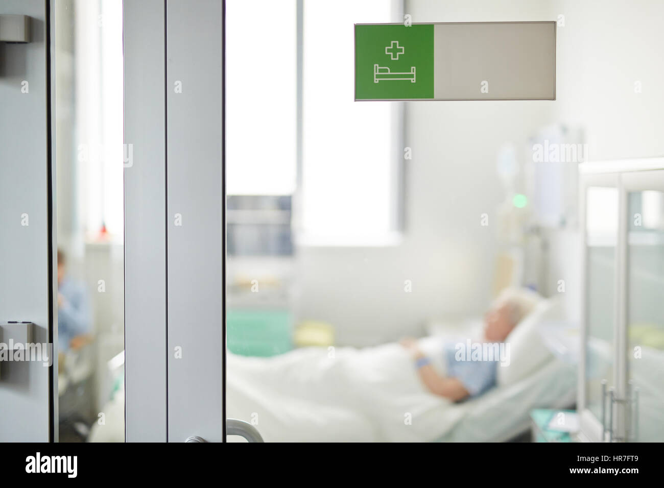 Hospital ward sign on closed glass door in clinic with blurred shape of ...