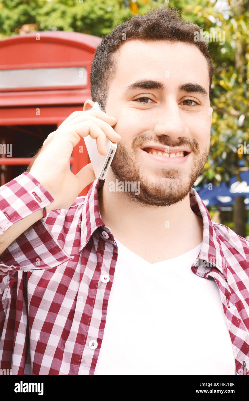 Portrait of young latin man talking on the phone. Outdoors. Urban scene ...