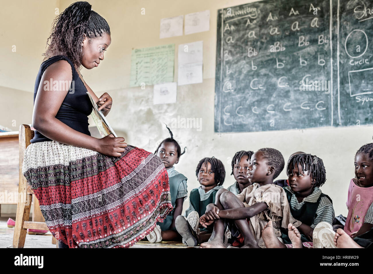 Children from a rural area leaning to read in front of their teacher in ...