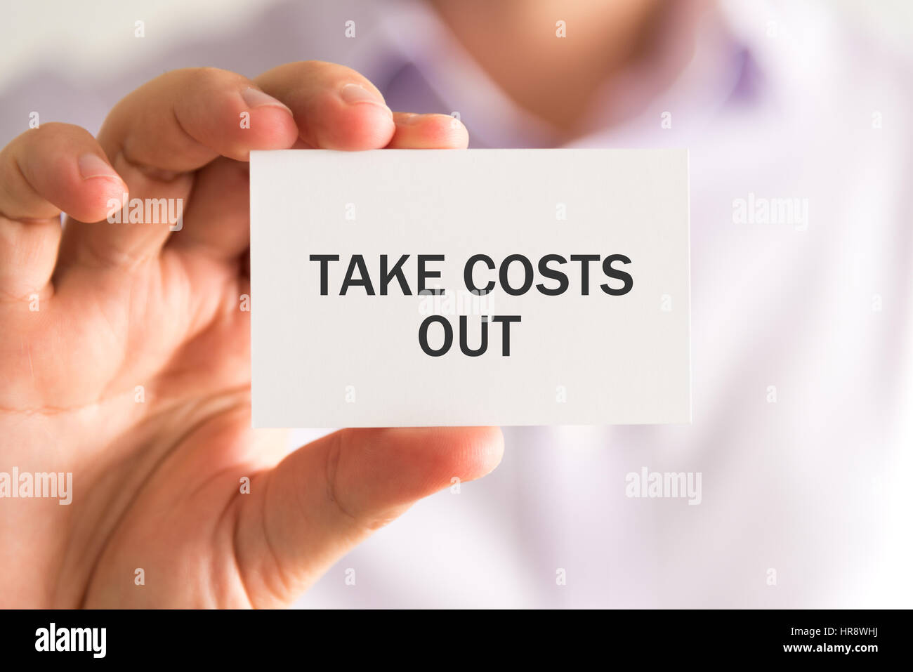 Closeup on businessman holding a card with TAKE COSTS OUT message ...