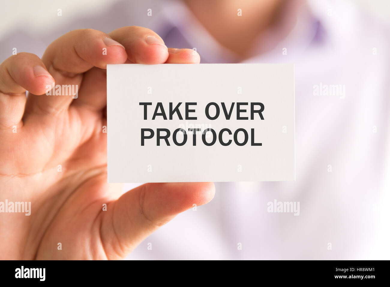 Closeup on businessman holding a card with TAKE OVER PROTOCOL message ...