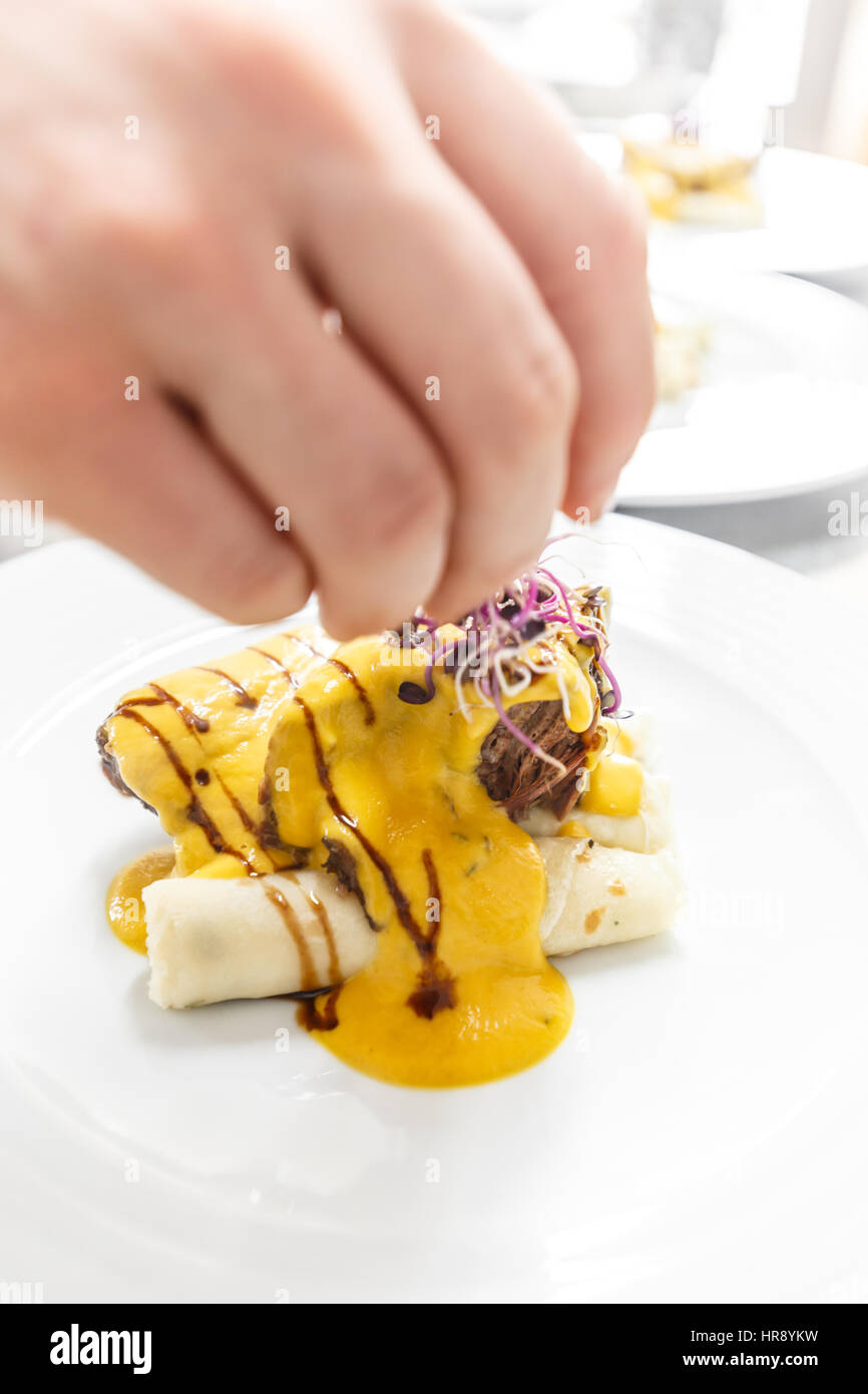 Chef finishing her plate and almost ready to serve at the table Stock ...