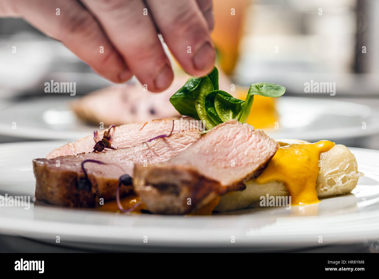 Chef finishing her plate and almost ready to serve at the table Stock ...