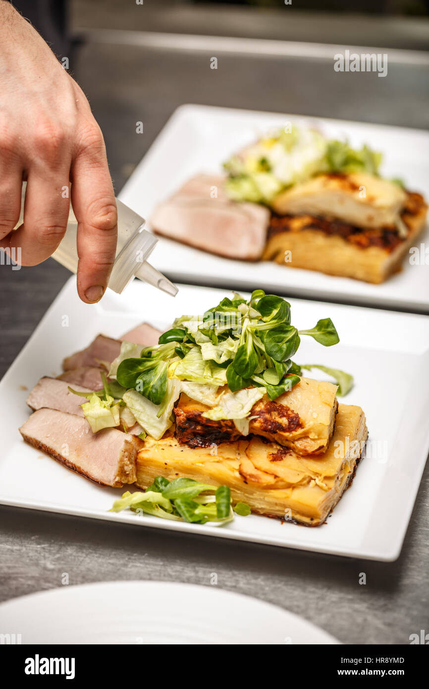 Chef adding finishing touch on his dish before it goes on the table ...