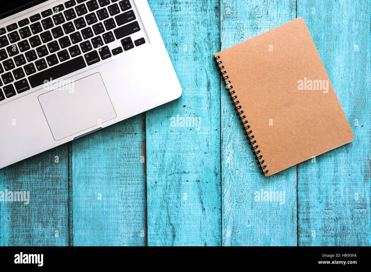 Blue wooden desk table with computer laptop and notebook. Top view with ...
