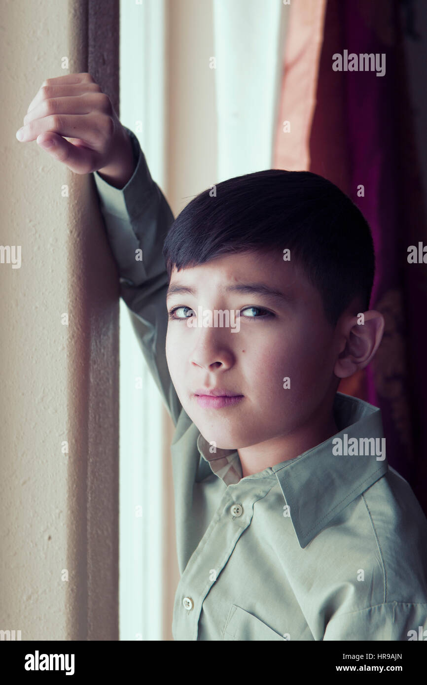 A confident young boy standing by a window Stock Photo - Alamy