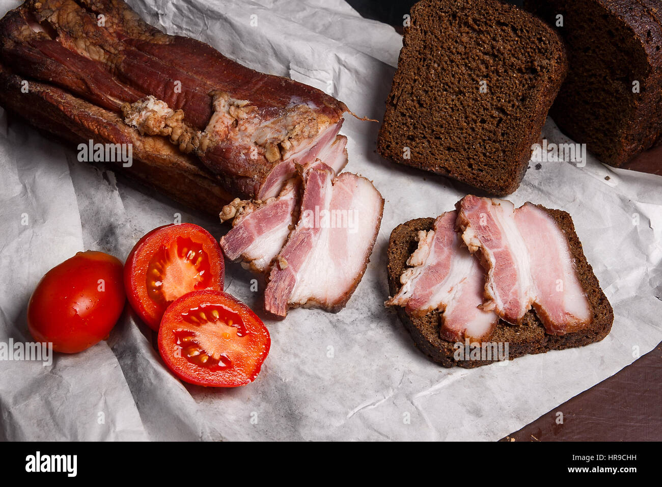 Close up view slices of smoked bacon with rye black bread on the white ...