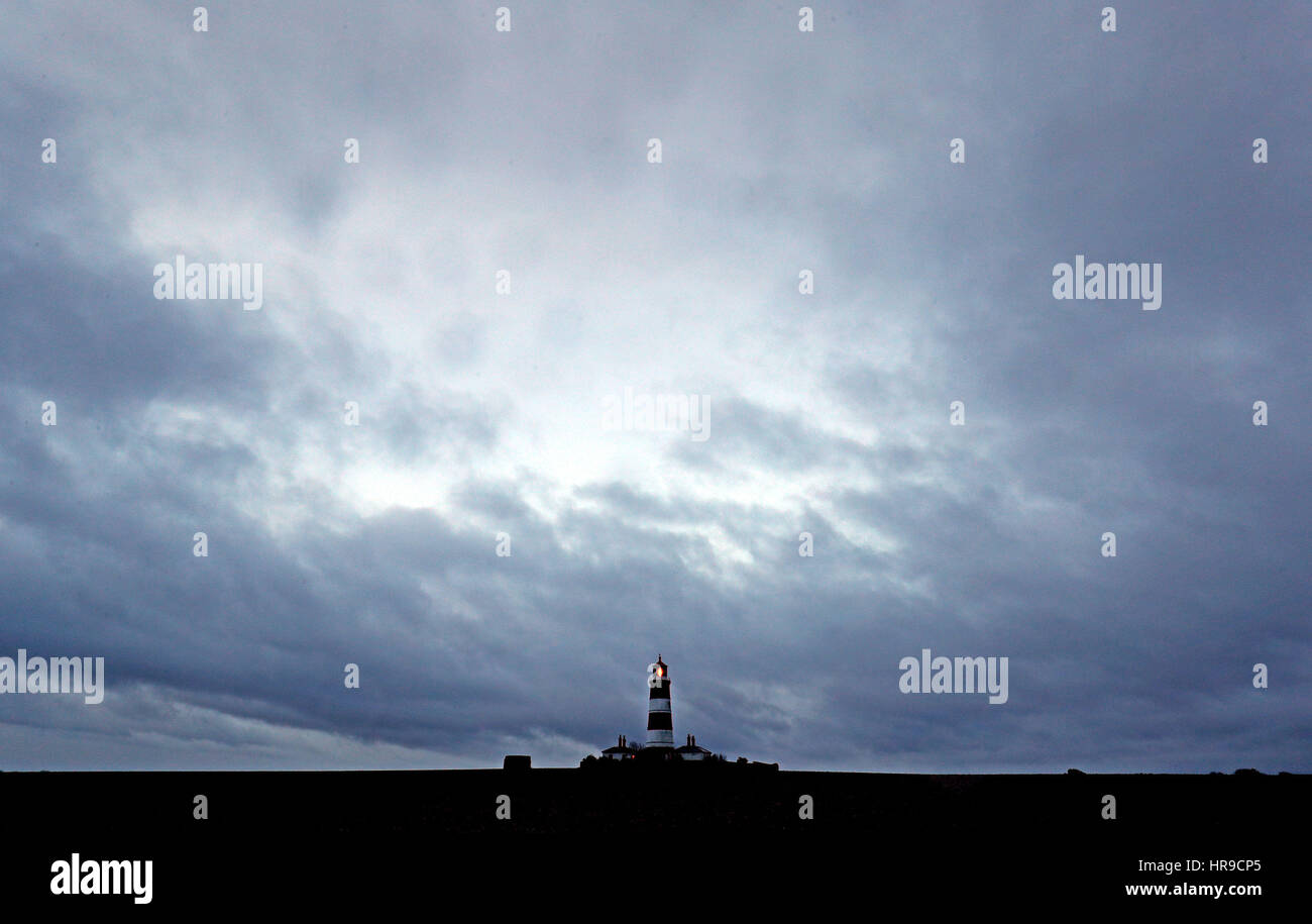 The lamp of the Happisburgh lighthouse is illuminated as dawn breaks ...