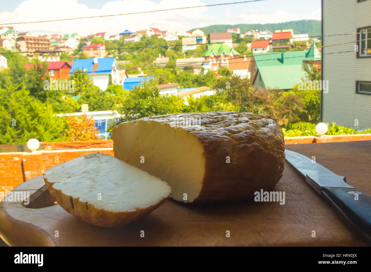 cut head of traditional Adygei cheese handmade with knife on wooden ...