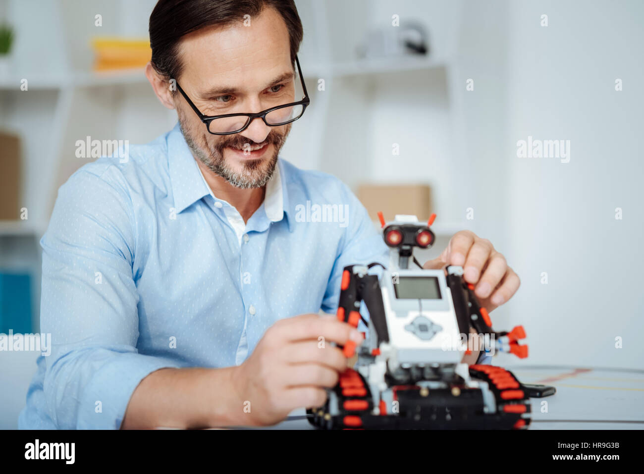 Positive engineer inspecting functions of robot Stock Photo - Alamy
