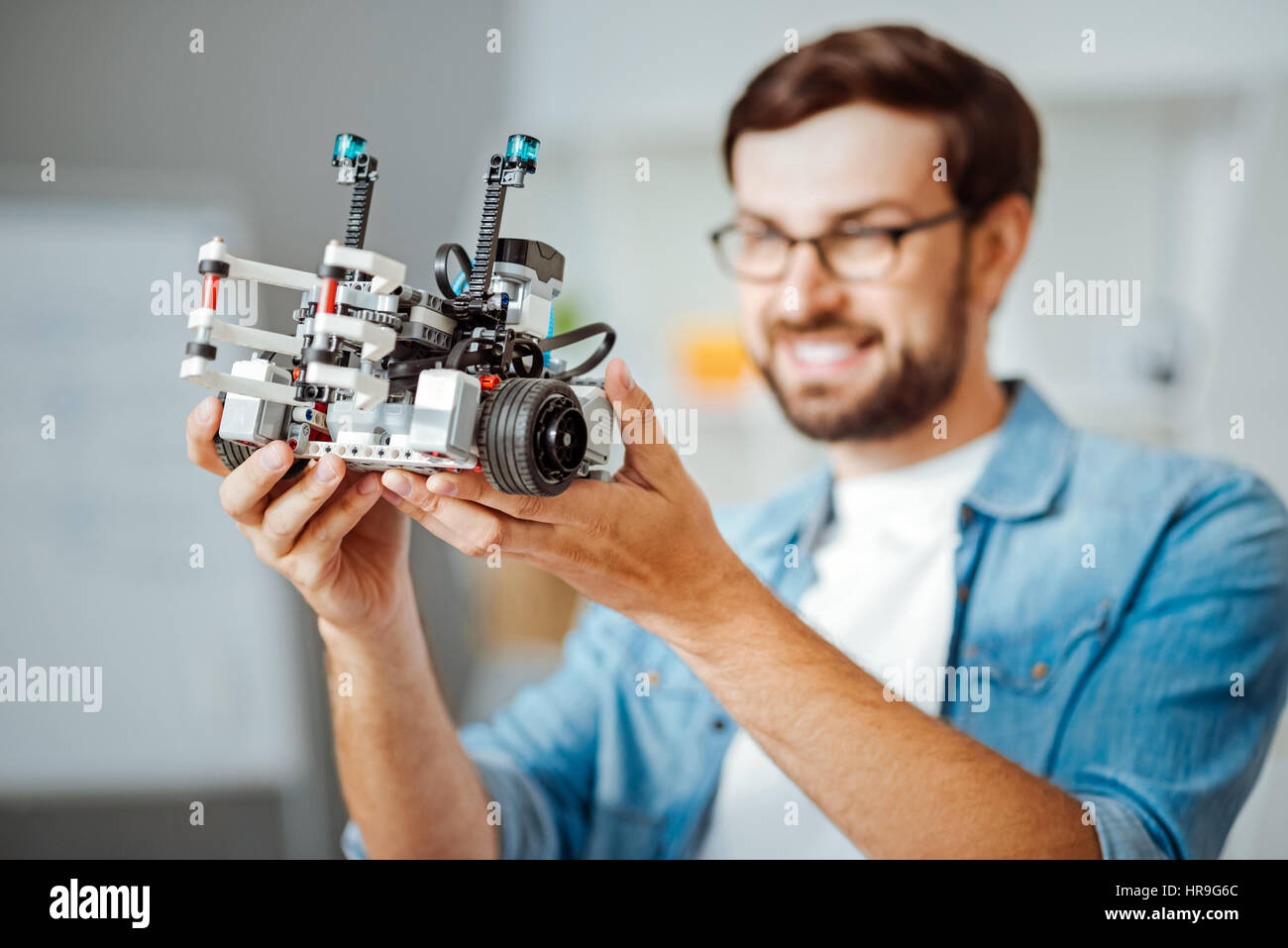 Positive professional engineer holding robot Stock Photo - Alamy