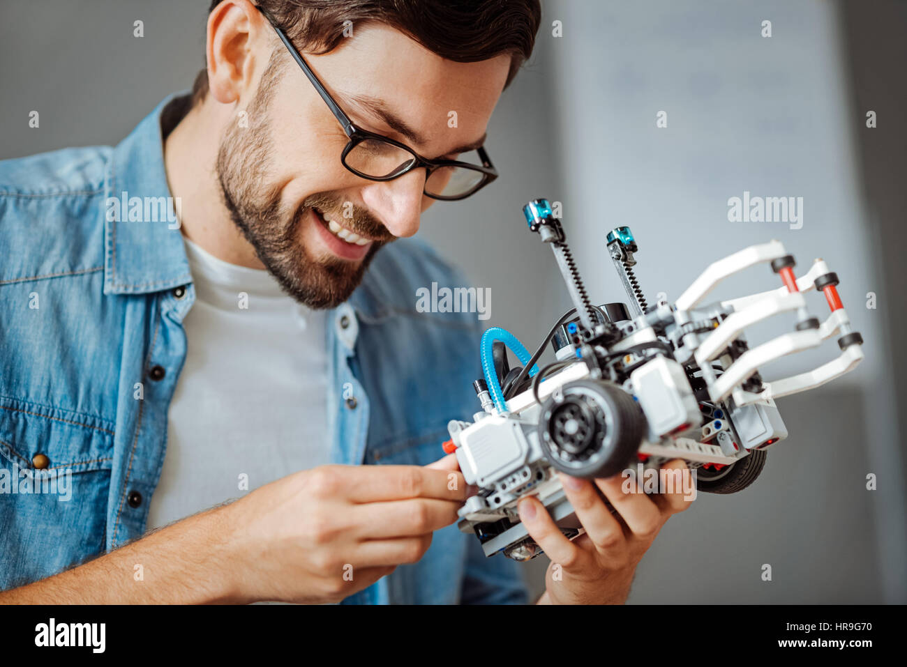 Smiling professional engineer holding robot Stock Photo - Alamy