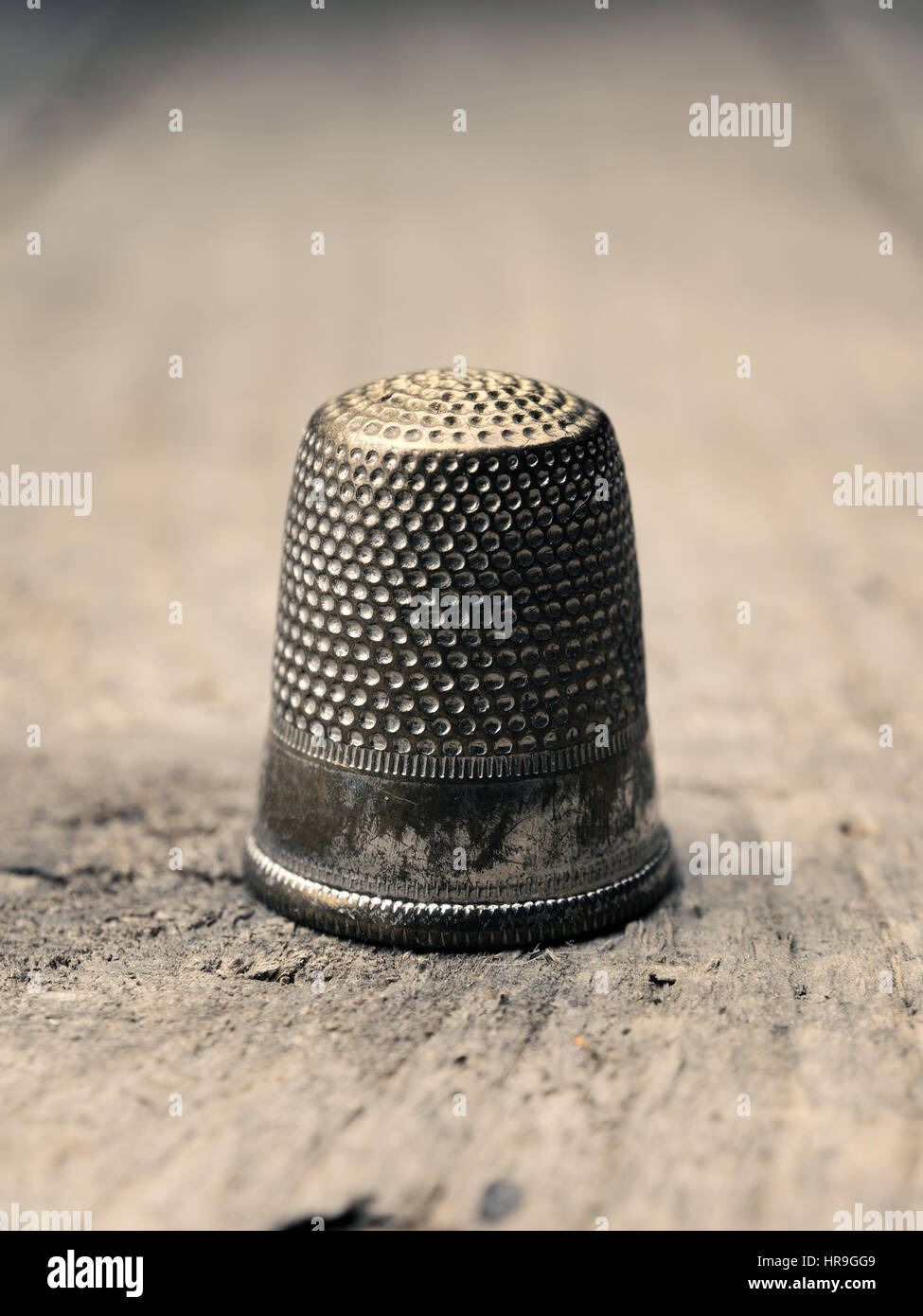 Old used thimble on an old rustic wooden table, close up shot with high ...
