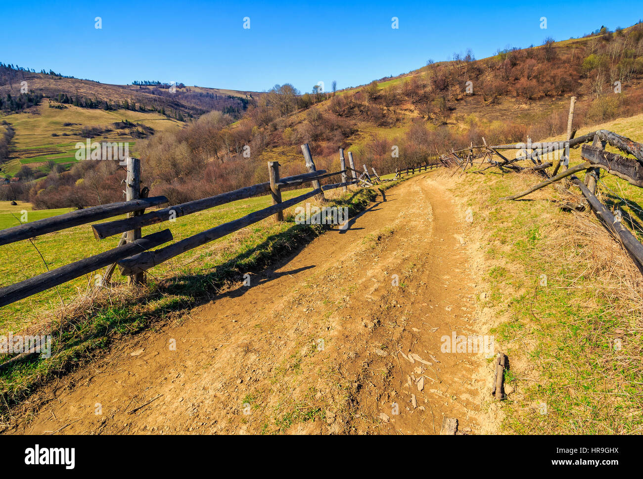 Spring time rural landscape. Wooden fence along the path through ...