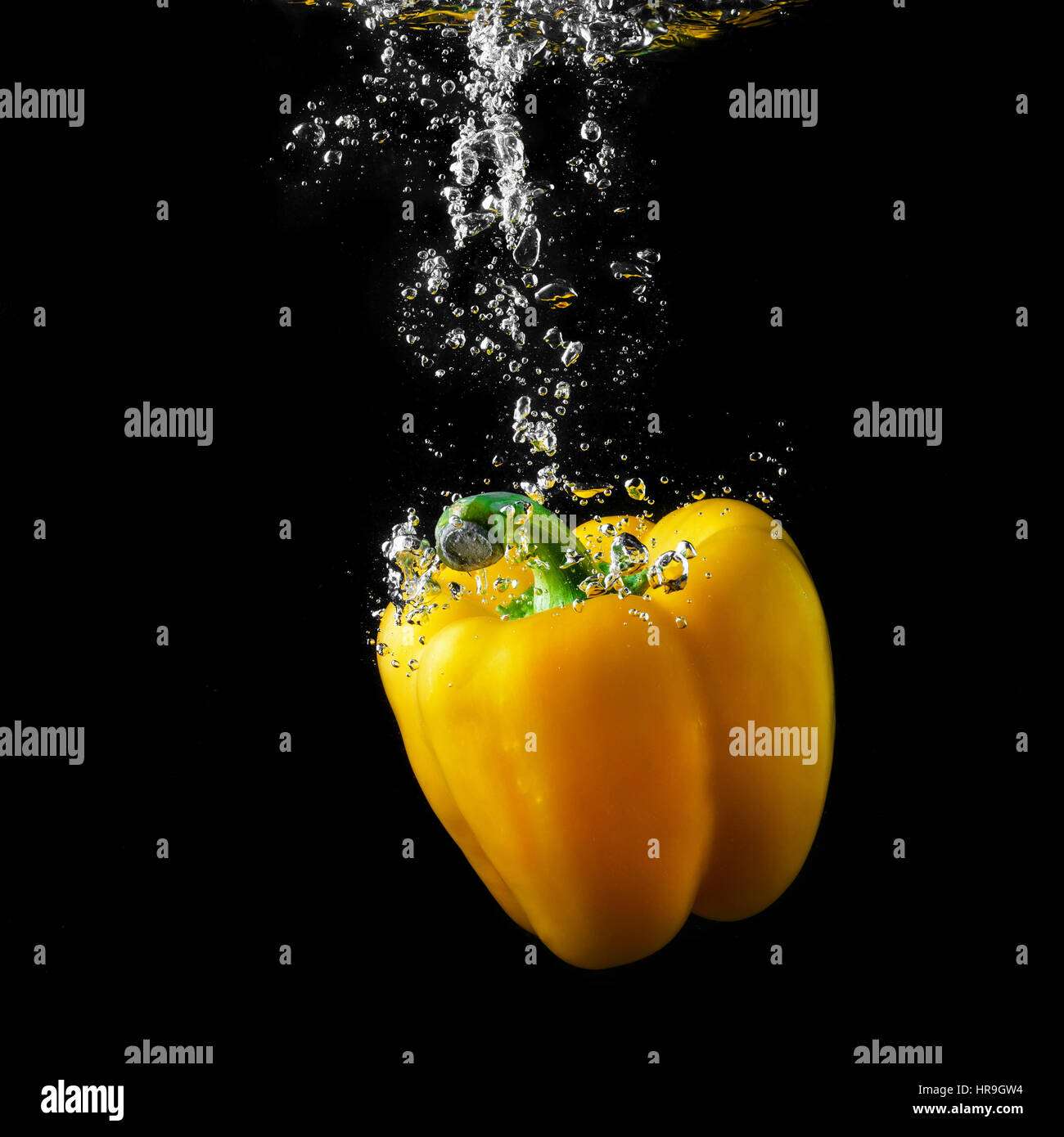 Fresh yellow paprika falling into the water with a splash and air ...