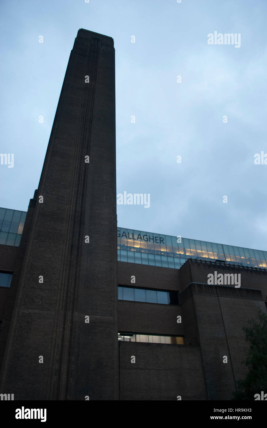 Dark central tower of Tate Modern art gallery against a pale blue sky ...