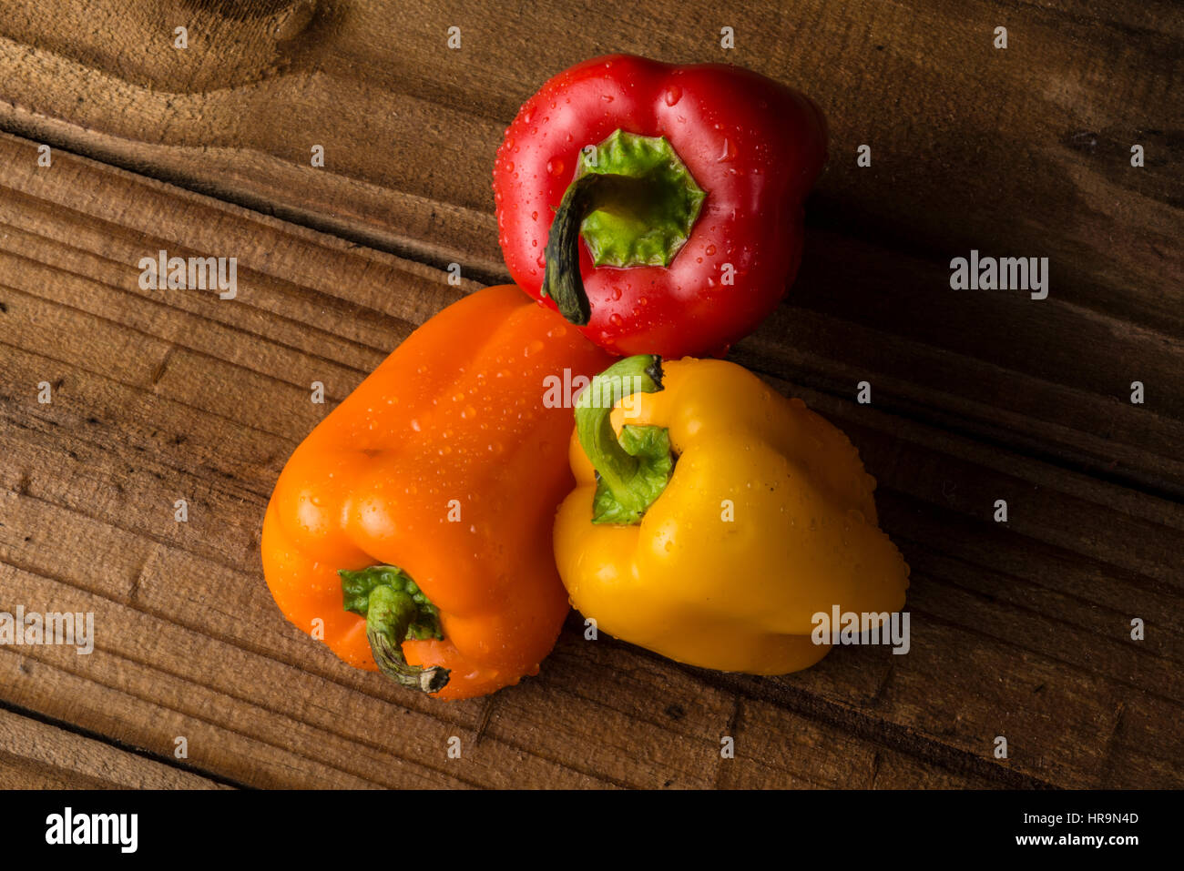 three peppers on wood table Stock Photo - Alamy