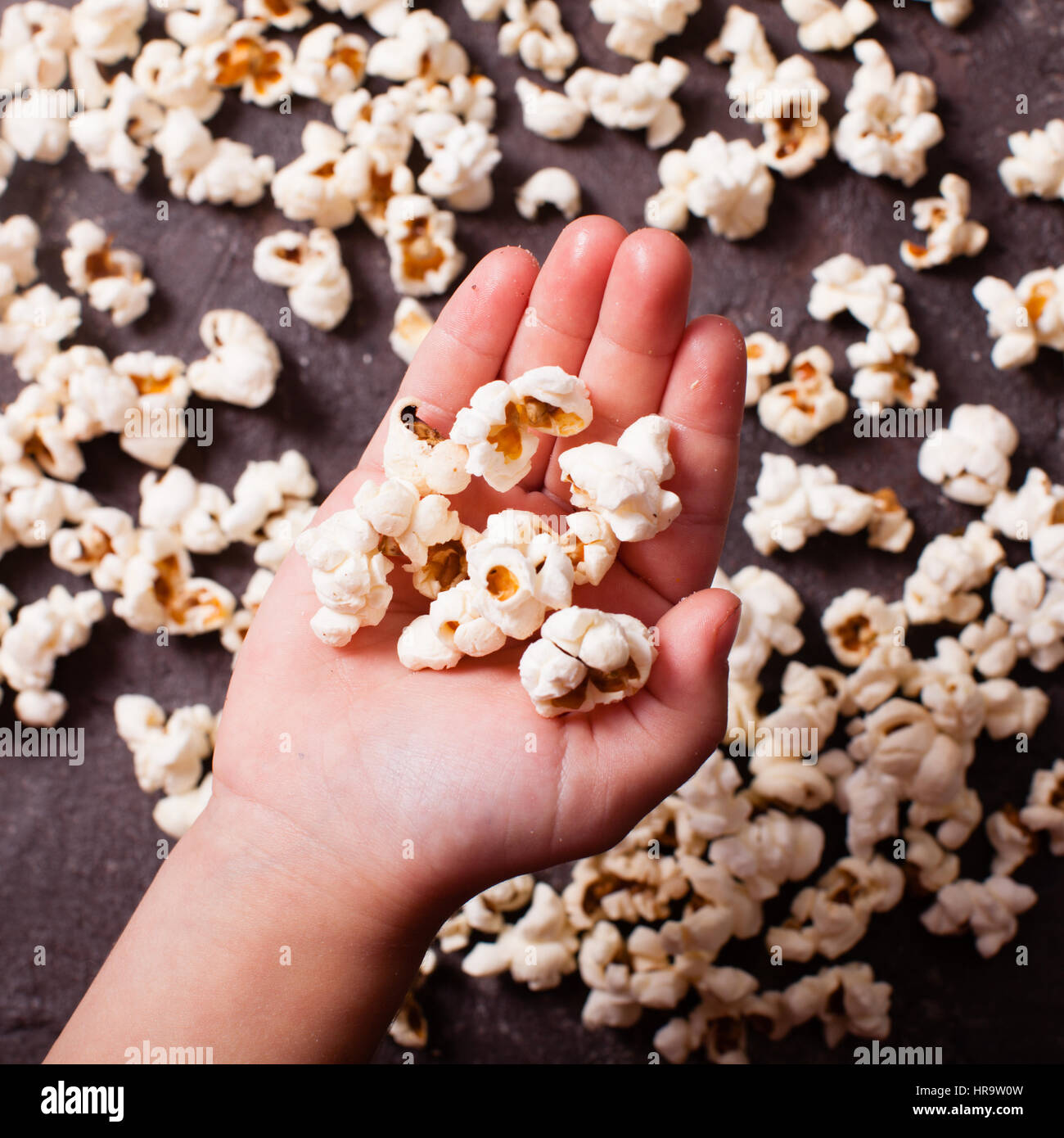 Children's hand holding a pile of fresh popcorn closeup Stock Photo - Alamy