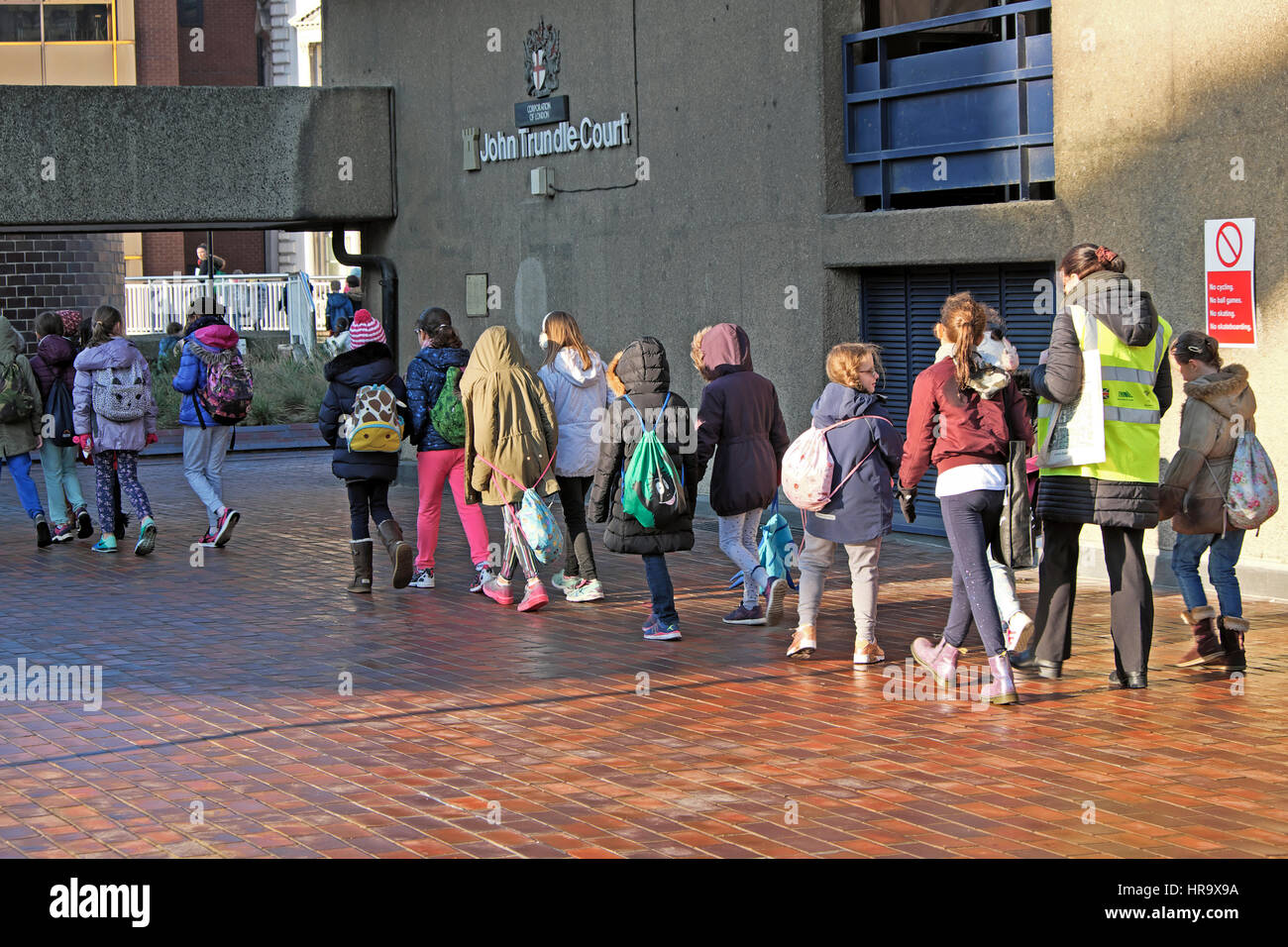 Primary school girls walking through a Barbican Estate courtyard with a ...
