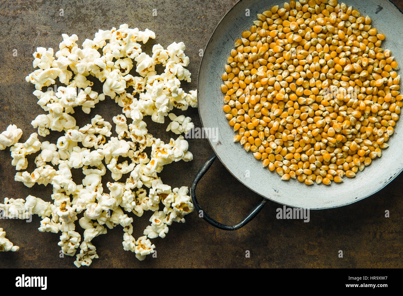 Popcorn and corn seeds on rusty background Stock Photo - Alamy