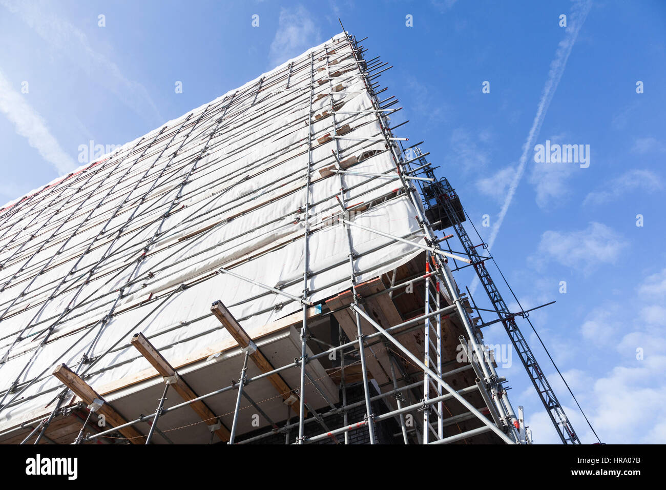 white cloth on scaffolding of high new building with elevator and blue ...