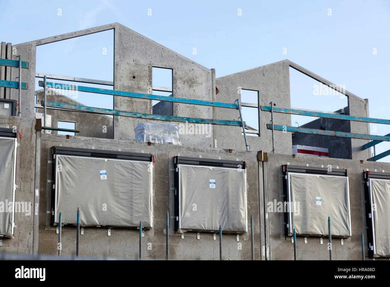 concrete frame of newly built house with scaffolding around and blue ...