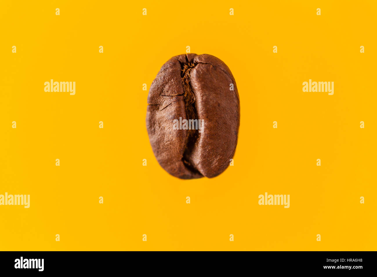 Single roasted arabica coffee bean on a yellow background Stock Photo ...