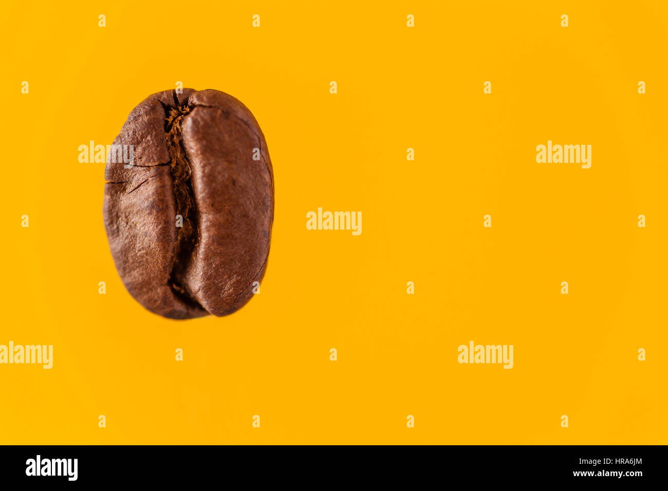 Single roasted arabica coffee bean on a yellow background Stock Photo ...