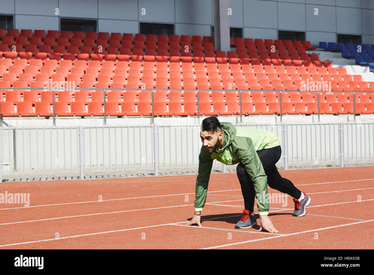 Middle Eastern male athlete ready to start running on stadiums sprint ...