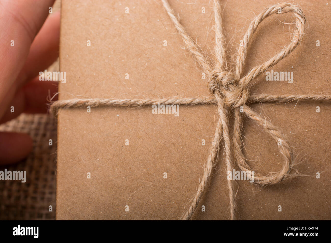 Hand holding a gift box of brown color on linen canvas Stock Photo - Alamy